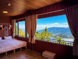 Quarto com uma cama grande, paredes de madeira e vista para as montanhas.