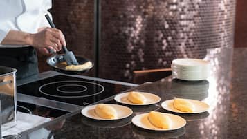 Uma cozinha com alguém cozinhando, uma pilha de pratos e um fogão de aço inoxidável.
