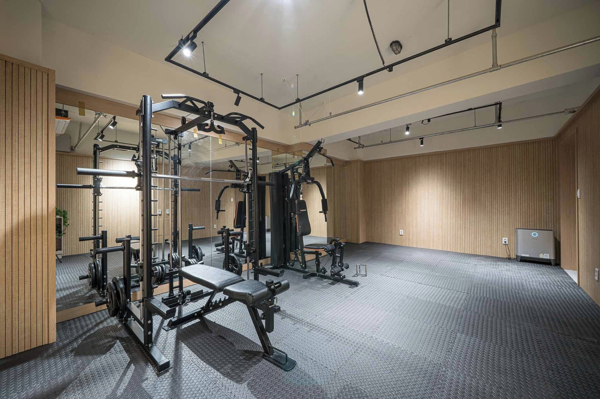 Uma academia com equipamentos de musculação, espelho e parede de madeira.