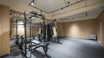 Uma academia com equipamentos de musculação, espelho e parede de madeira.