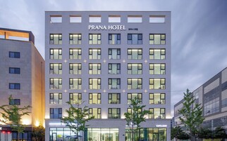 Um edifício de hotel moderno com fachada plana, várias janelas e um café e bar no nível térreo.
