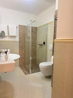 Quarto Duplo Deluxe, vista para o pátio | Casa de banho | Um polibã, artigos de higiene pessoal grátis, um secador de cabelo 