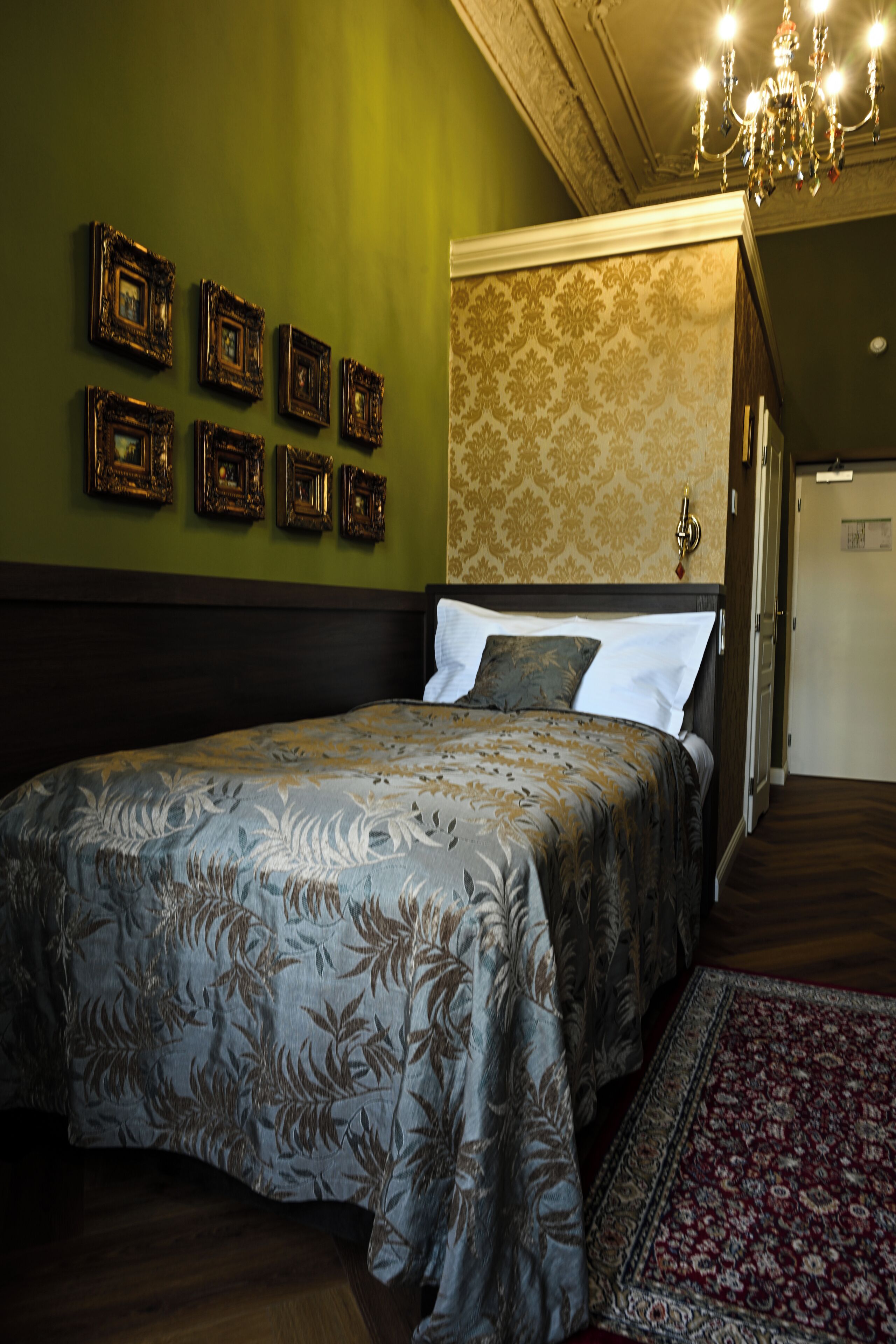 Um quarto com uma cama grande, parede estampada e um lustre.