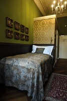 Um quarto com uma cama grande, parede estampada e um lustre.