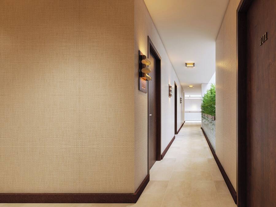 Corredor de hotel com paredes estampadas, piso ladrilhado e portas identificadas com números de quarto.
