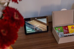 Um tablet exibindo uma mensagem em italiano, uma superfície de madeira e uma caixa com sacos de café.