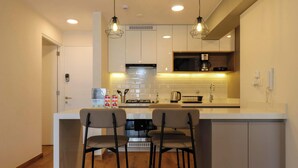 Cozinha moderna com ilha central, dois banquetes, iluminação pendente e forno embutido.