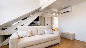Uma sala de estar moderna com um sofá, um banco e uma escada.