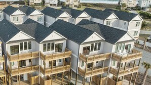 Um edifício residencial à beira-mar, com várias varandas, telhado plano e vista para o oceano.