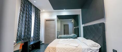 Quarto moderno com cama, mesas de cabeceira, escrivaninha e espelho.