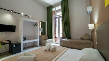 Quarto de hotel com cama, escrivaninha, televisão e janela com cortinas.