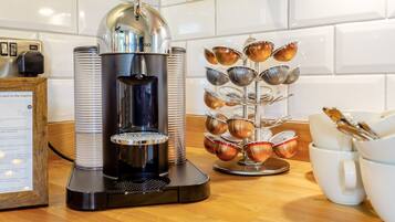 Máquina de café com bandeja coletora, jarra de café e suporte para xícaras com várias unidades.