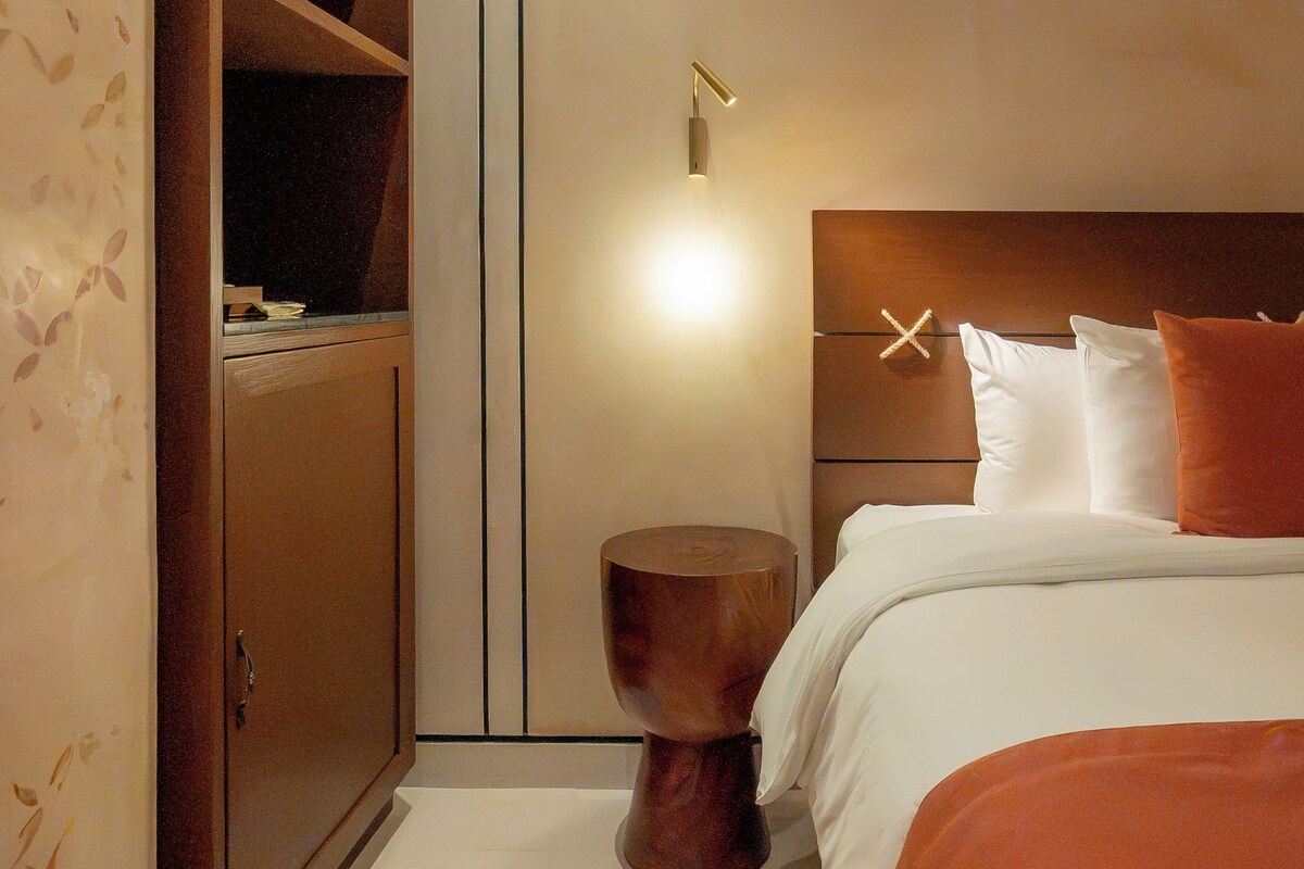 Quarto com cama, mesa de cabeceira e guarda-roupa.