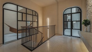 Um interior moderno com escada, divisórias de vidro e uma planta.