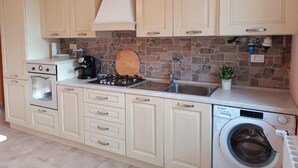 Um frigorífico, um forno, uma placa de cozinha, utensílios de cozinha 