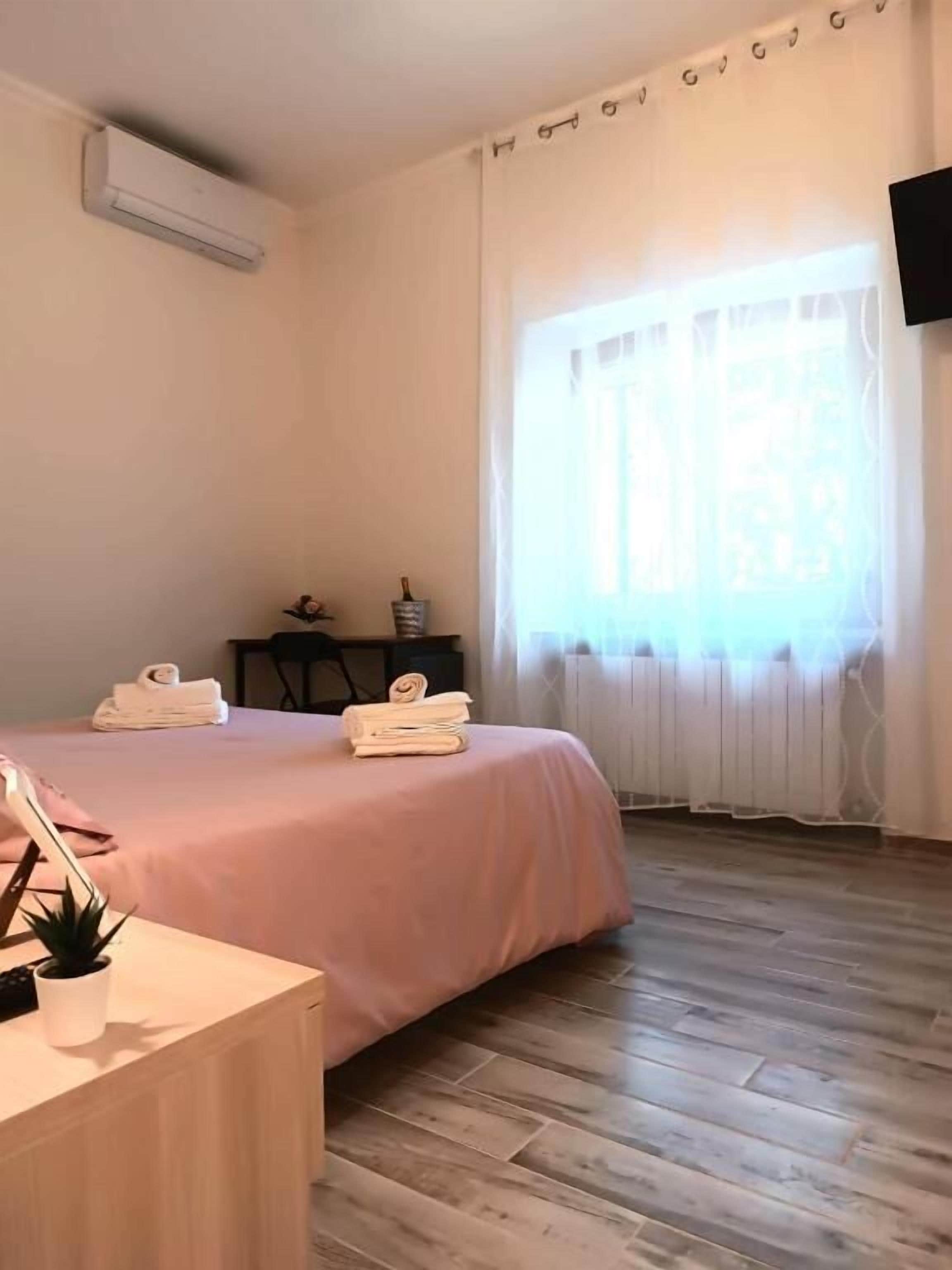 Quarto de hotel com cama, escrivaninha e janela com cortinas.