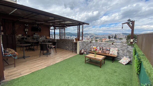 Um terraço no telhado com deck de madeira, área de estar e vista para a paisagem urbana.
