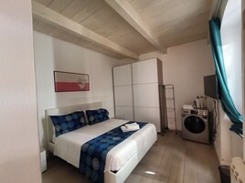 Quarto com cama, máquina de lavar, televisão e guarda-roupa.
