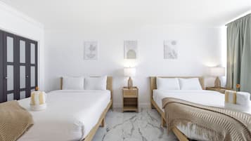 Quarto de hotel com duas camas, um guarda-roupa, uma mesa de cabeceira com abajur e uma pintura na parede.