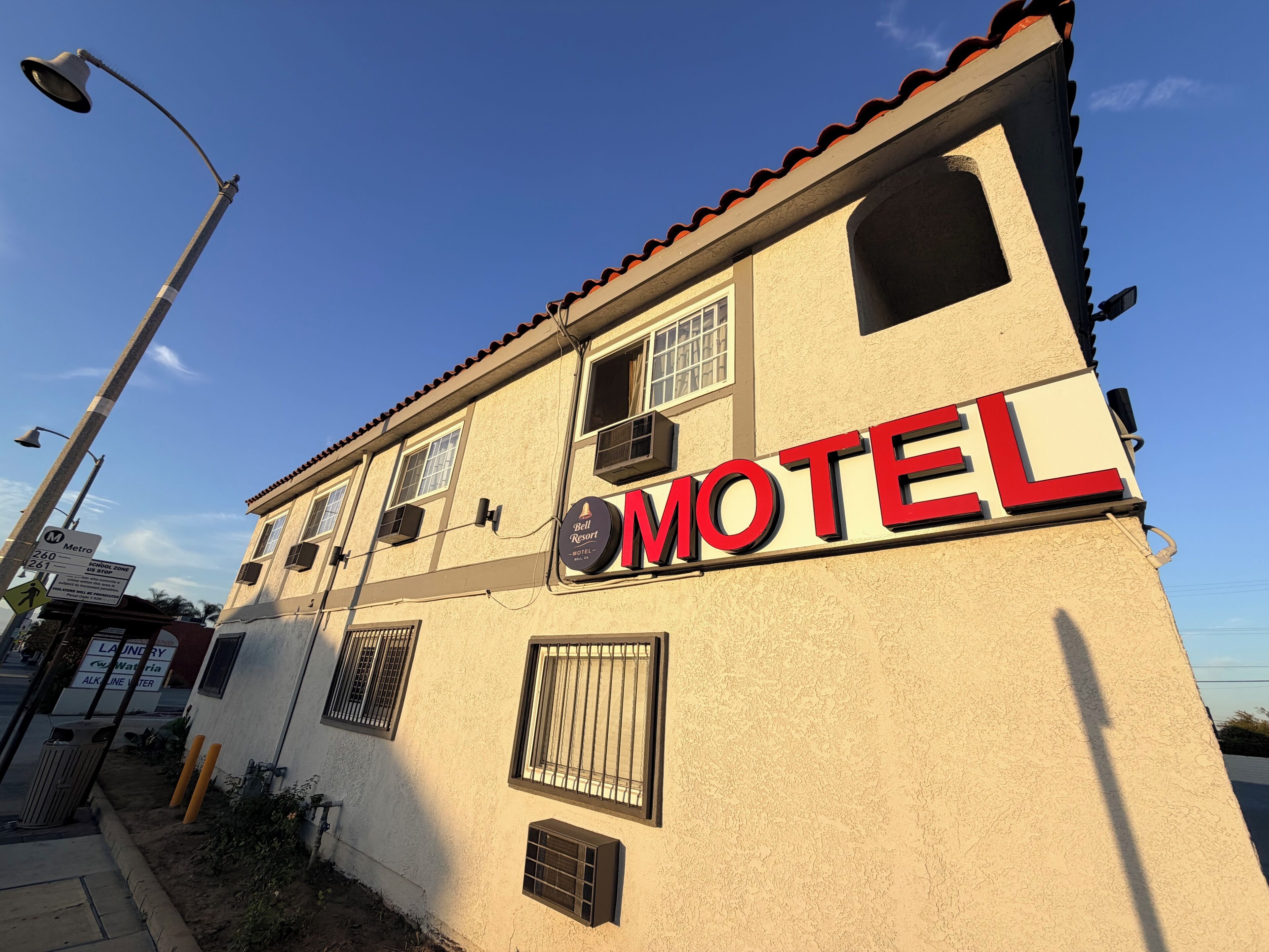 Um edifício com uma placa que diz 'Motel' e um letreiro em forma de sino indicando 'Bell Motel'.