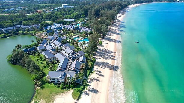 Vista aérea de um resort à beira-mar, com propriedades na orla, piscina e praia.