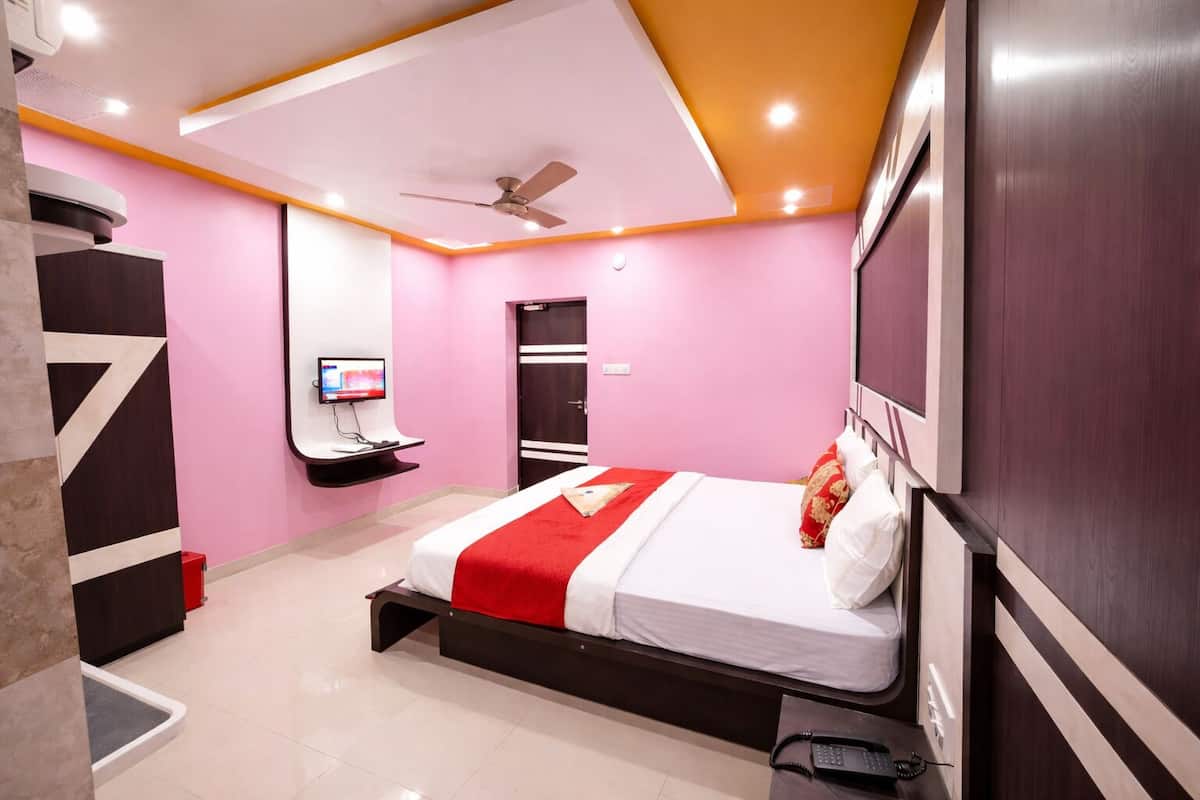 Quarto de hotel moderno com cama, televisão, ventoinha no teto e porta.