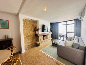 Apartamento Deluxe, vista parcial para o mar | Sala de estar | Televisor de 40 polegadas com canais digitais 