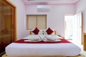 Quarto de hotel com cama, guarda-roupa de madeira, janela com persianas, unidade de ar condicionado e porta para o exterior.
