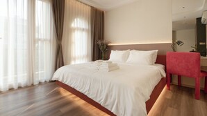 Quarto de hotel com uma cama grande, uma escrivaninha e uma cadeira.