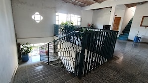 Interior com vários níveis, escada, corrimão de metal e plantas em vasos.