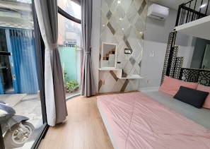 Quarto com cama, mesa de cabeceira, espelho e janela com cortinas.