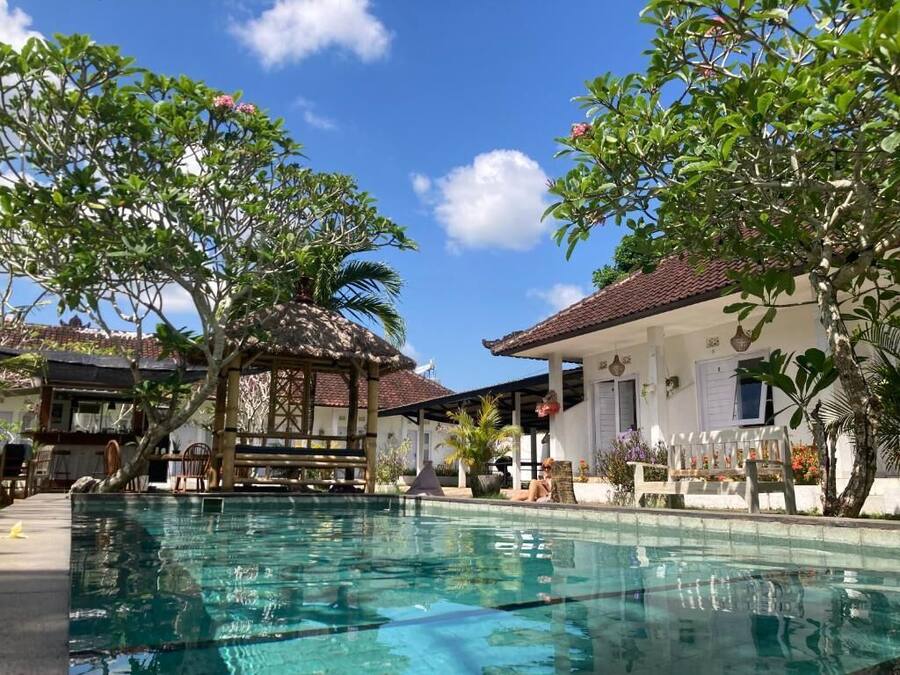 Uma área de piscina com uma piscina azul cristalina, cercada por vegetação exuberante e arquitetura tradicional.