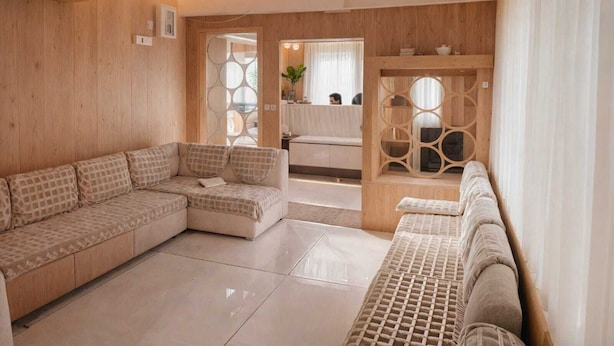 Uma sala moderna com um sofá modular, um sofá pequeno e uma estante de madeira decorativa.