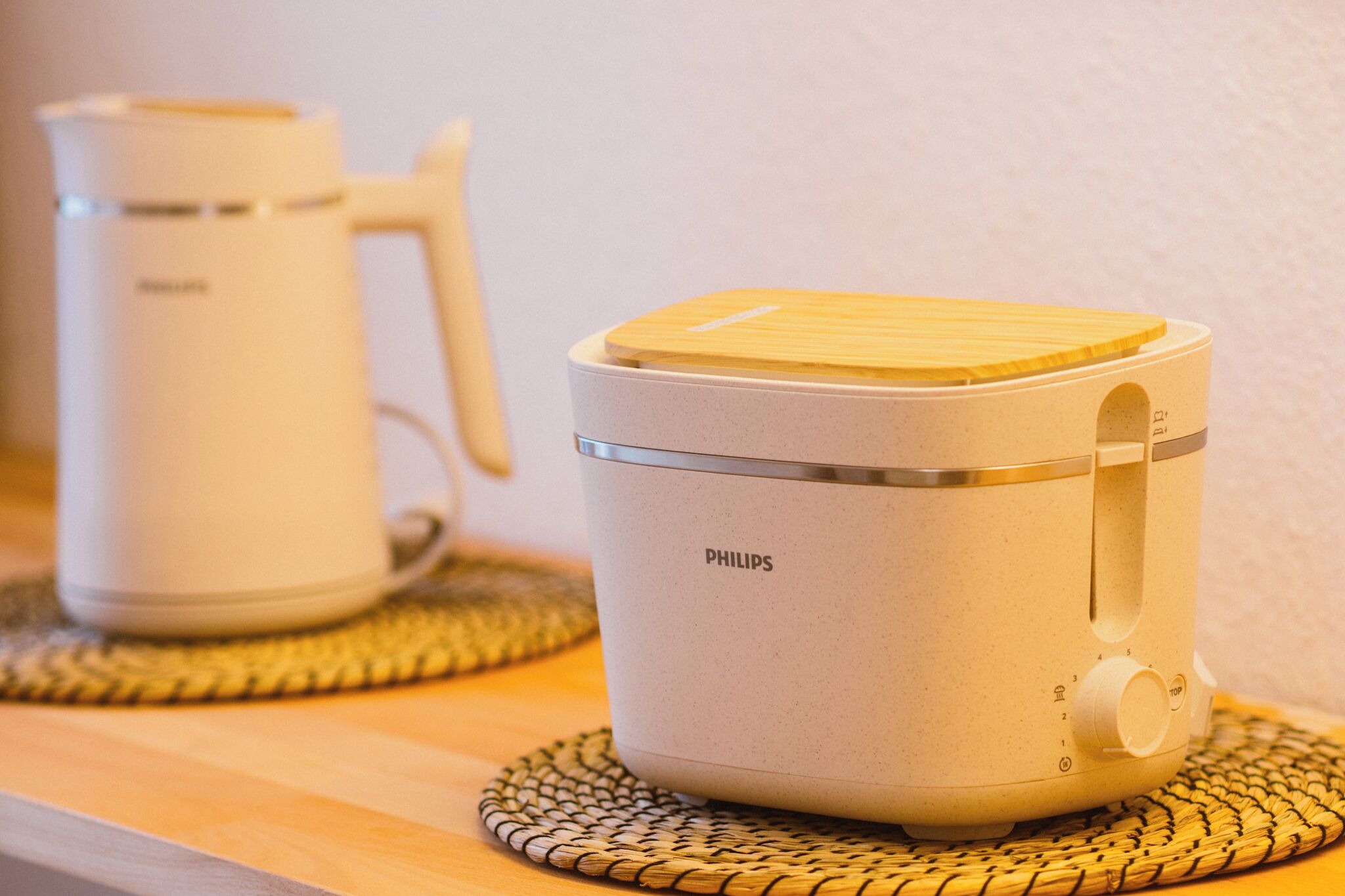 Uma cafeteira Philips e uma caneca branca sobre um descanso de tecido.
