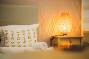 Uma cama bem arrumada com travesseiro estampado e mesa de cabeceira com abajur texturizado.
