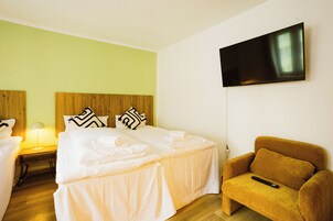 Quarto de hotel com duas camas, uma televisão e um sofá.