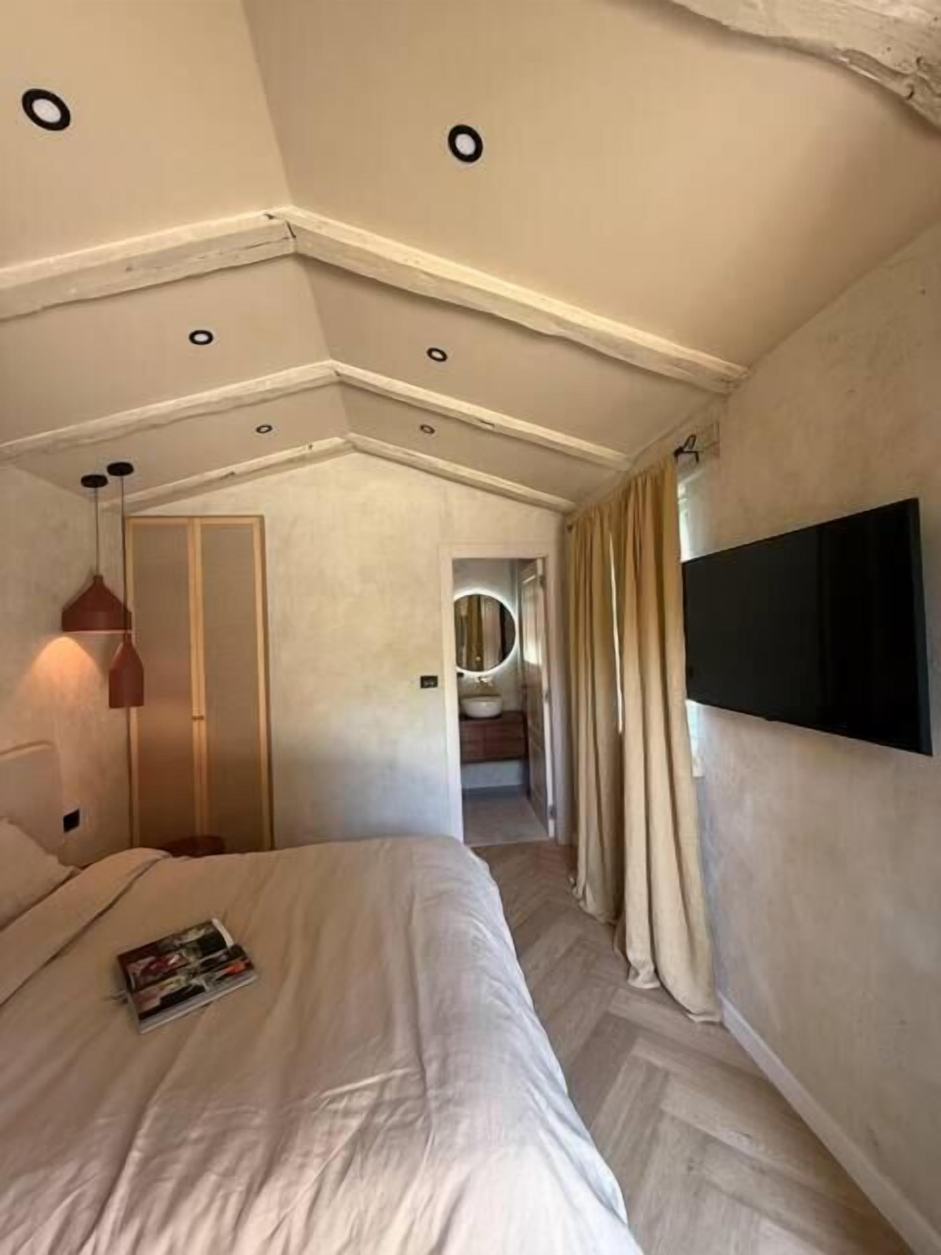 Quarto com cama, televisão na parede e teto com iluminação embutida.