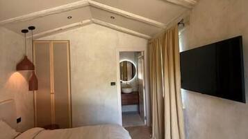 Quarto com cama, televisão na parede e teto com iluminação embutida.