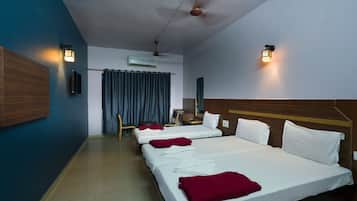 Quarto de hotel com duas camas, ventoinha no teto, luminárias fixadas na parede, unidade de ar condicionado e cabeceira de madeira.