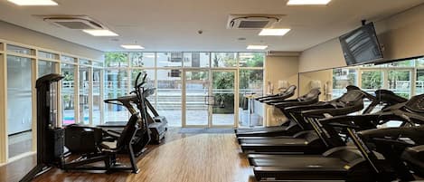 Uma academia com esteiras, bicicleta ergométrica e aparelho de musculação.