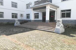 Um edifício com entrada coberta e escadas que levam a ele, com duas estátuas.
