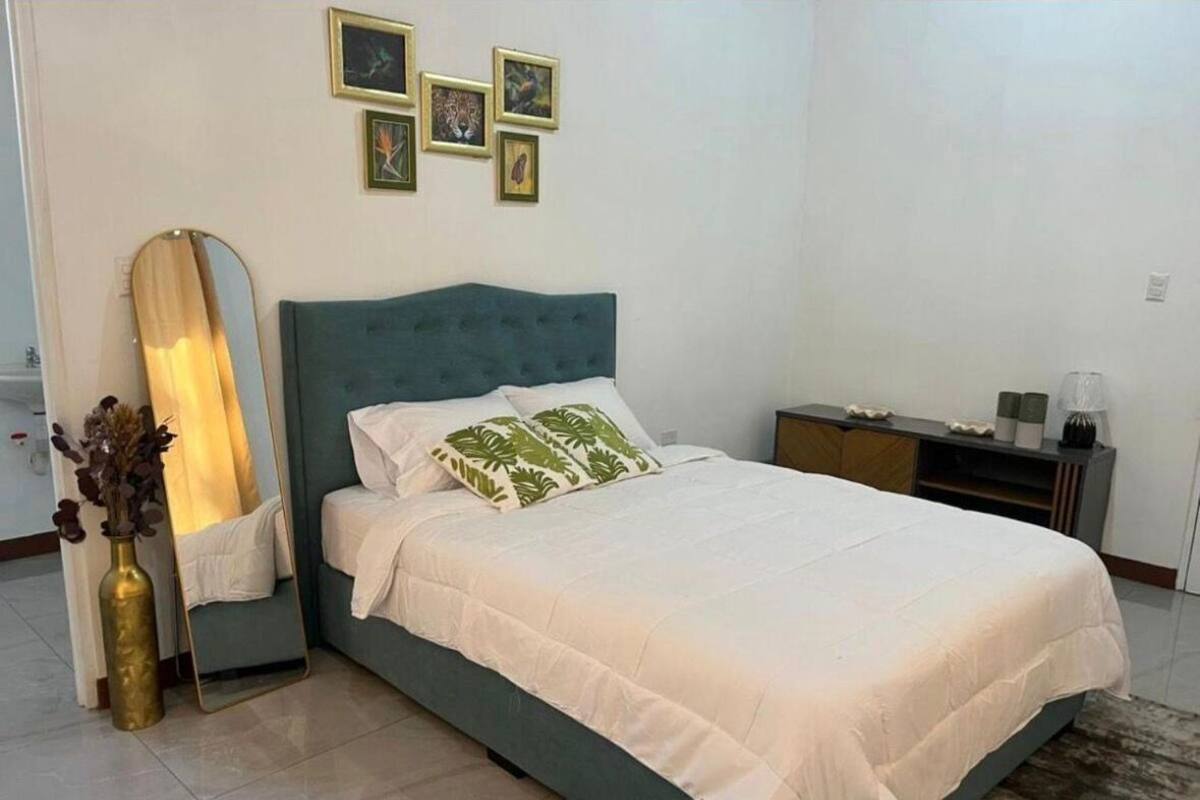 Quarto com cama, mesa de cabeceira, espelho e obras de arte na parede.