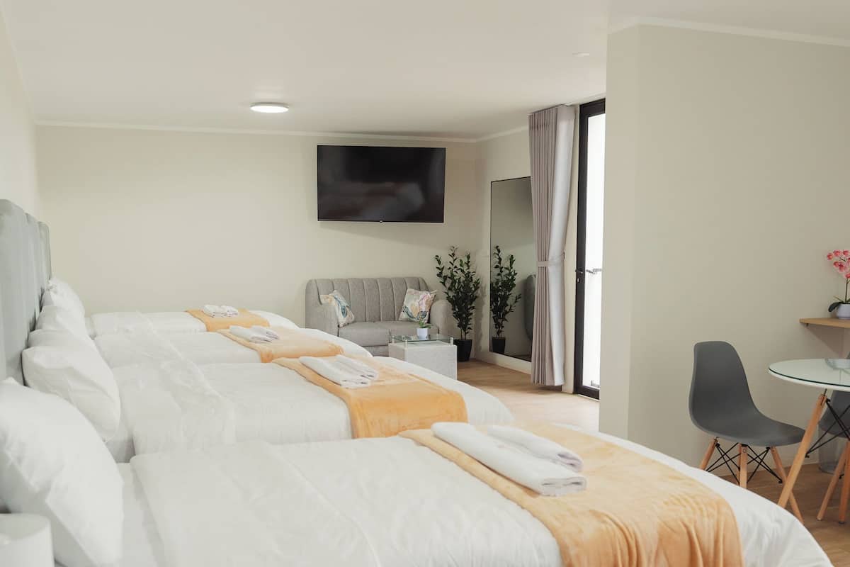 Quarto de hotel com cama grande, escrivaninha, cadeira, televisão e janela com cortinas.