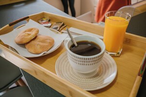 Uma bandeja com dois biscoitos, uma xícara de café e um copo de suco de laranja.