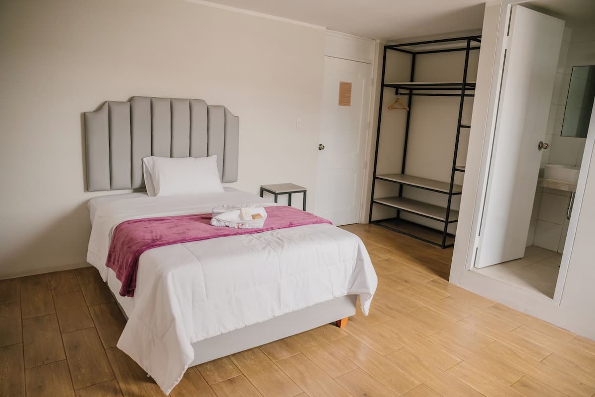 Quarto bem organizado com cama, mesa de cabeceira e armário embutido.
