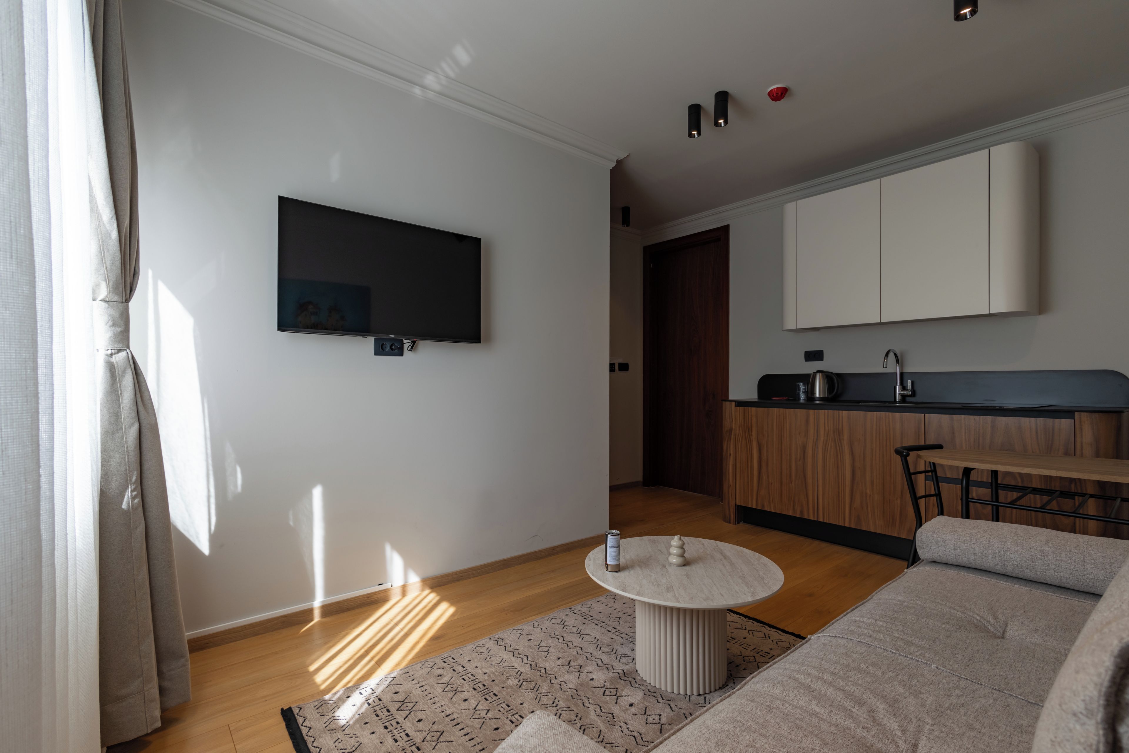 Uma sala de estar moderna com televisão de tela plana, mesa de centro redonda e um sofá.