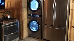 Cozinha com fogão de aço inoxidável, forno duplo, máquina de lavar e refrigerador.