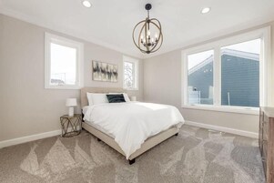 Quarto com cama grande, lustre, janela e pintura na parede.