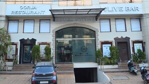Um edifício com uma placa indicando 'Oorja Restaurant' e 'Olive Bar' no andar térreo.