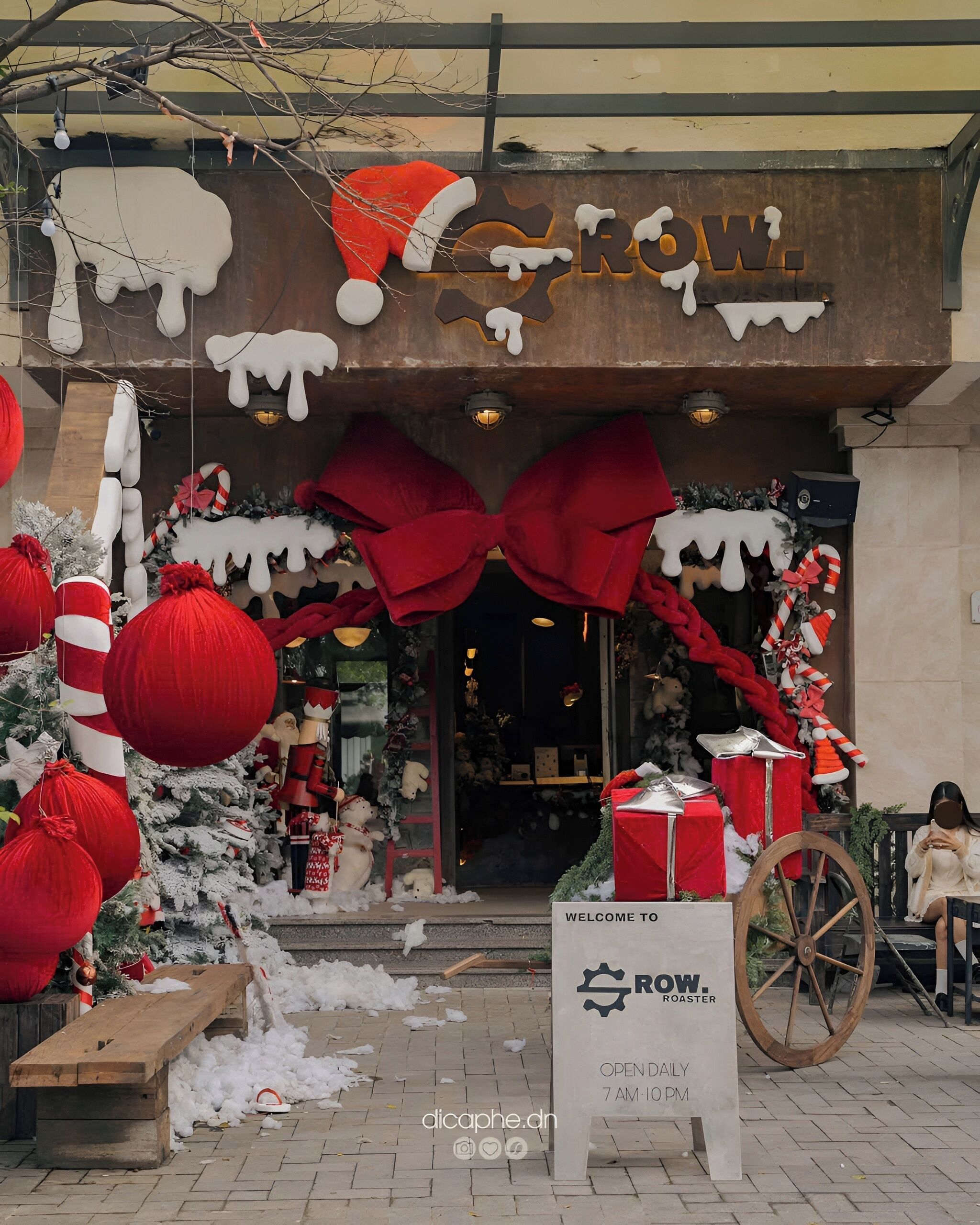 Fachada de loja com o letreiro 'ROW ROASTER', decorada com laços vermelhos, gorros de Papai Noel e gotas que parecem neve.